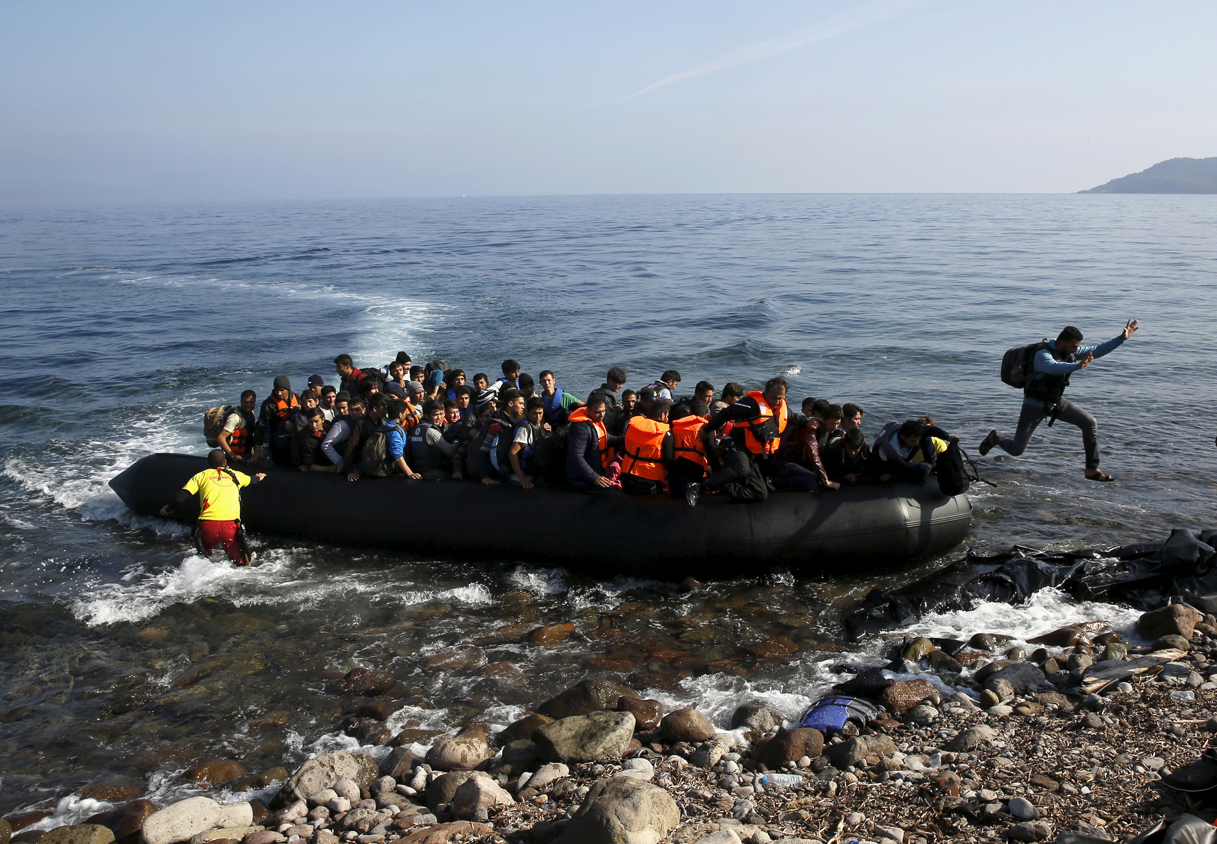 PRINT An Afghan migrant jumps off an overcrowded raft onto a beach at ...